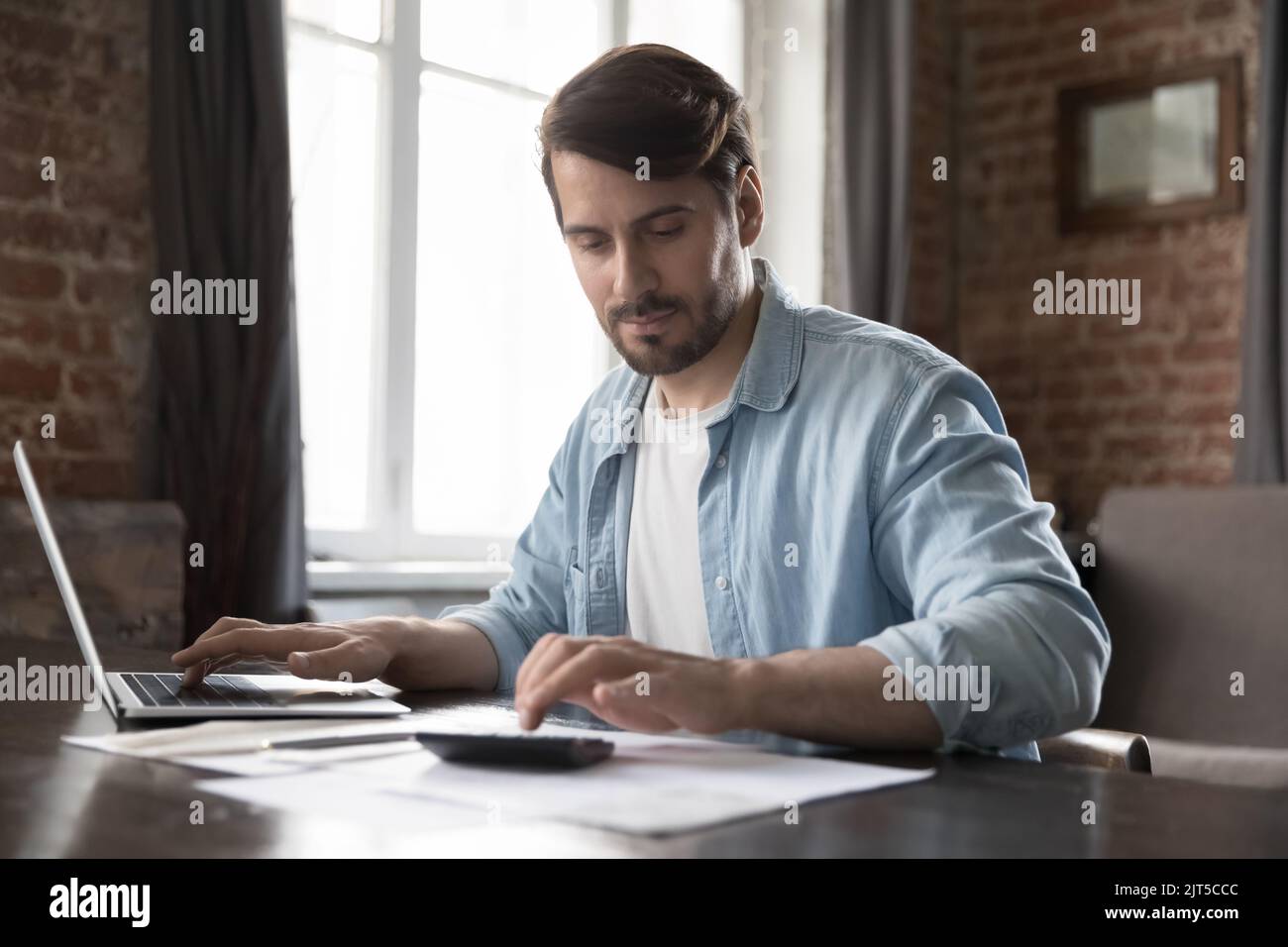 Handsome business owner man calculating project expenses, using laptop ...