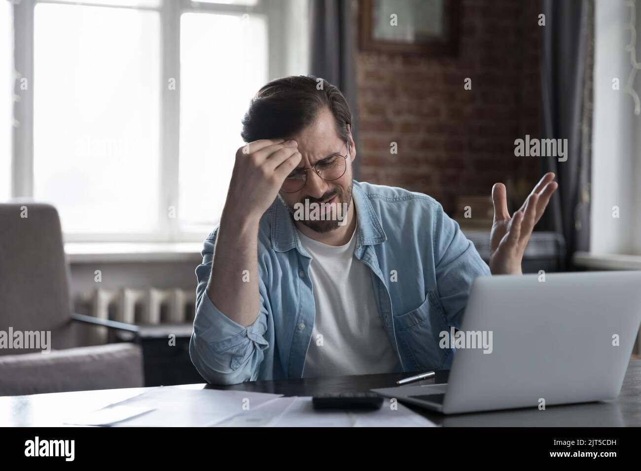 Desperate upset laptop user man sitting at paper bills, documents Stock ...