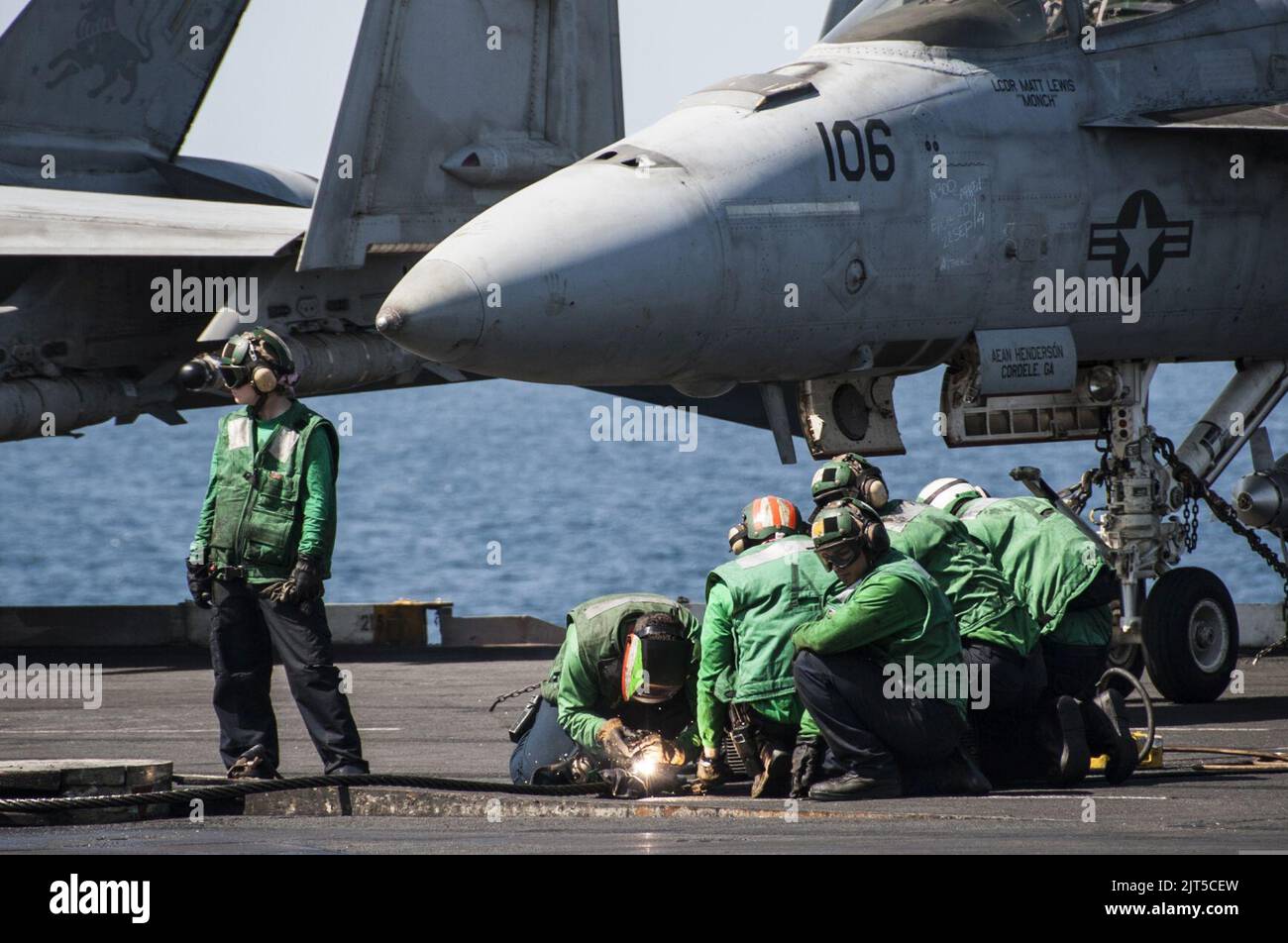 U.S. Sailors perform maintenance on arresting gear aboard the aircraft ...