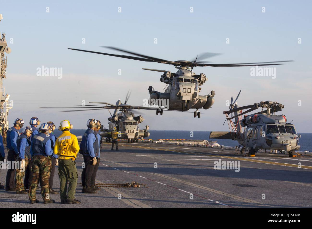 U.S. Sailors watch as a Marine Corps CH-53E Super Stallion helicopter ...