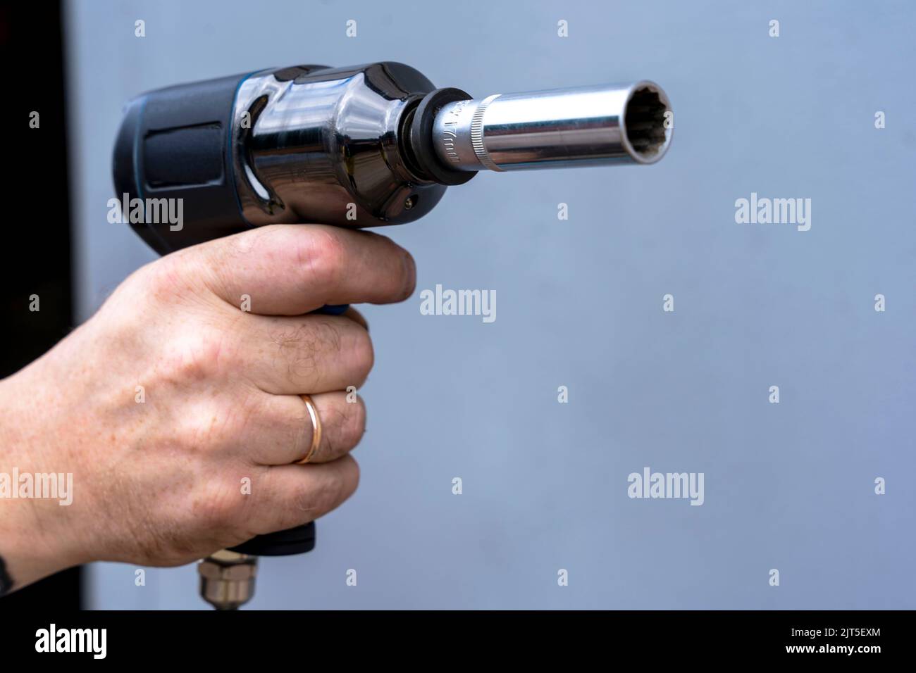 a pneumatic impact wrench with an end head in the hand of a master ...