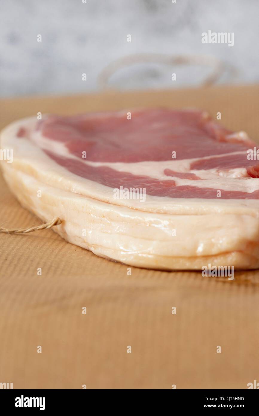 Raw smoked thick cut bacon slices wrapped in brown paper with string ...