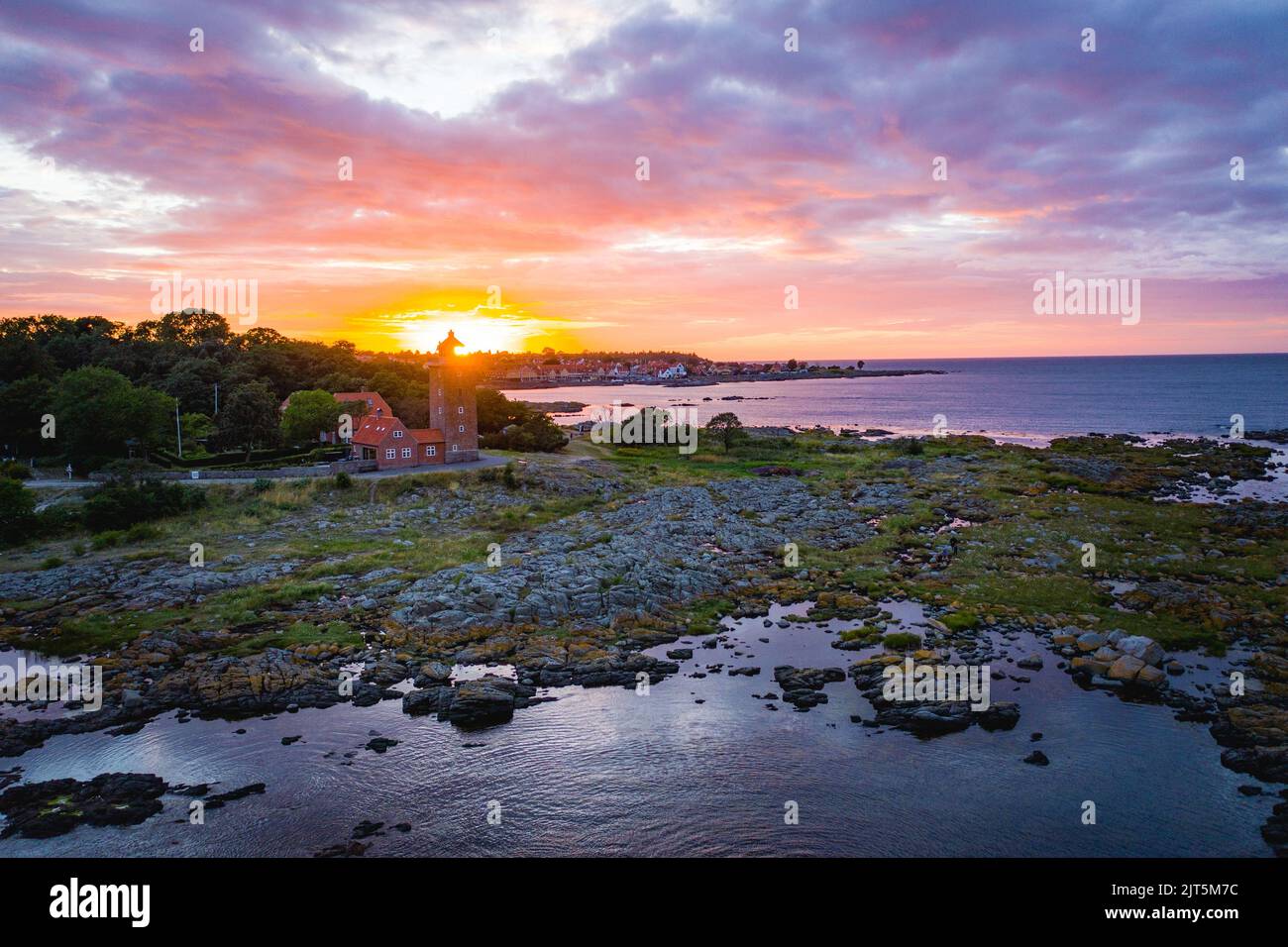 aerial view of svaneke lighthouse at coast during sunset on island ...