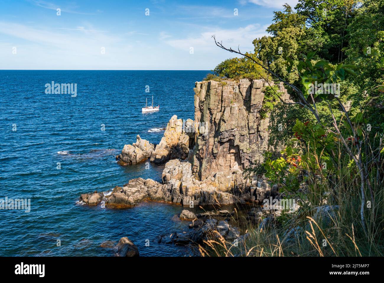Boat passing by Sanctuary Cliffs of the northern coast of Bornholm ...