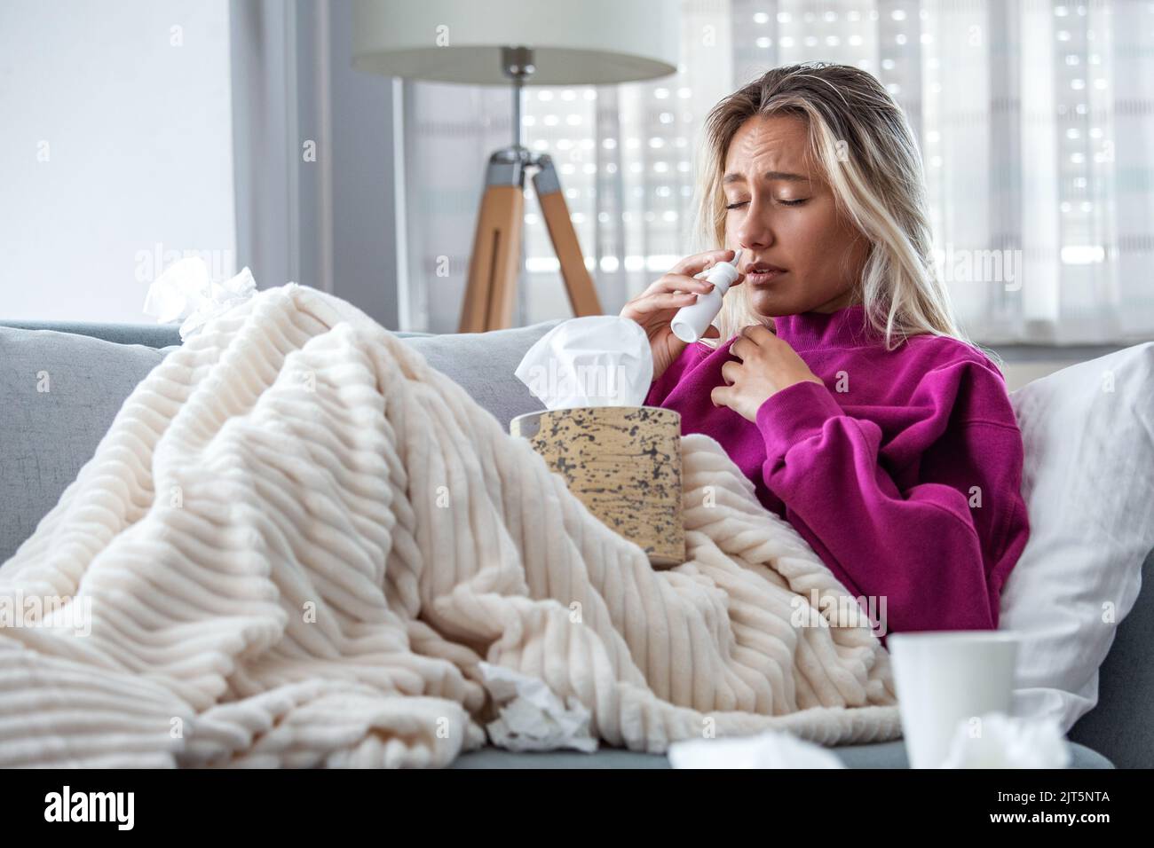 Woman is having flu and she is using nasal spray to help herself. Woman ...