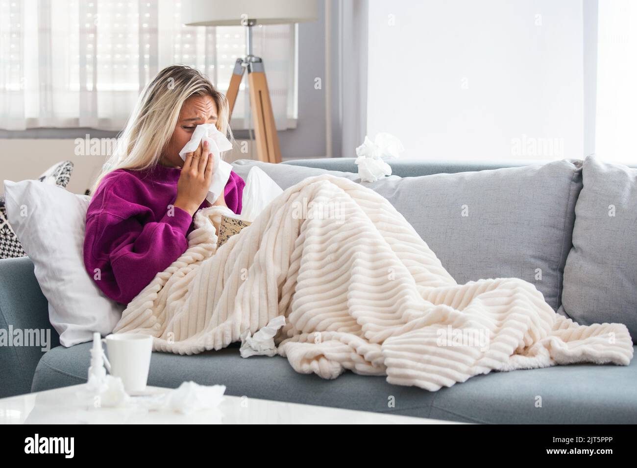 Sick day at home. Blonde woman has runny and common cold. Cough ...