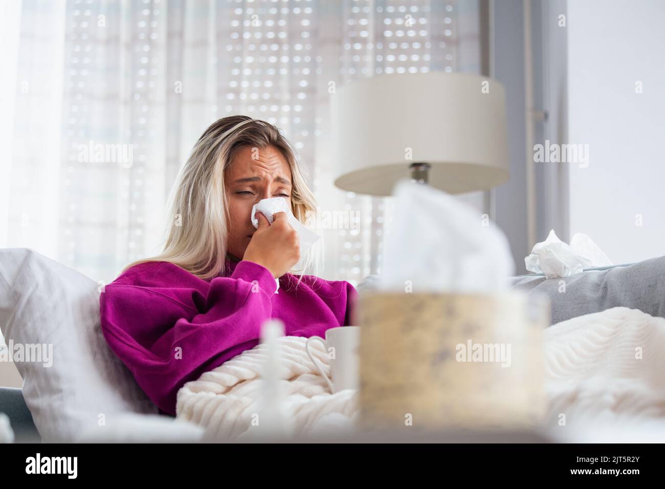 Sick day at home. Blonde woman has runny and common cold. Cough ...