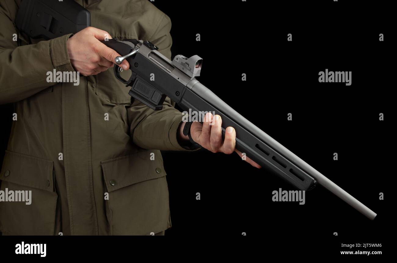 A man in a khaki jacket holds a bolt rifle with a reflex sight in his ...