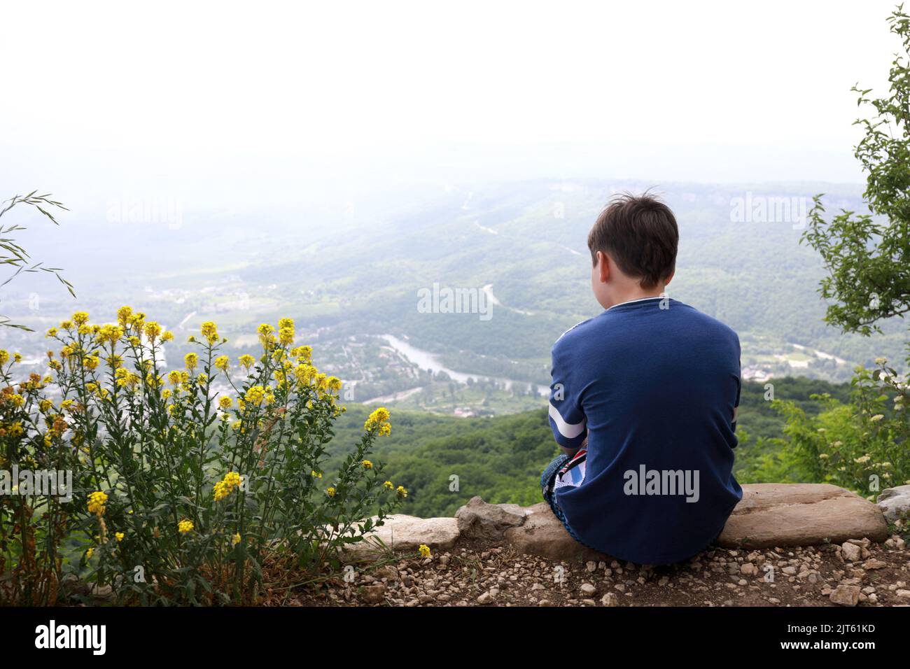Boy resting on rock of Una-koz ridge in Caucasus, Adygea Stock Photo ...