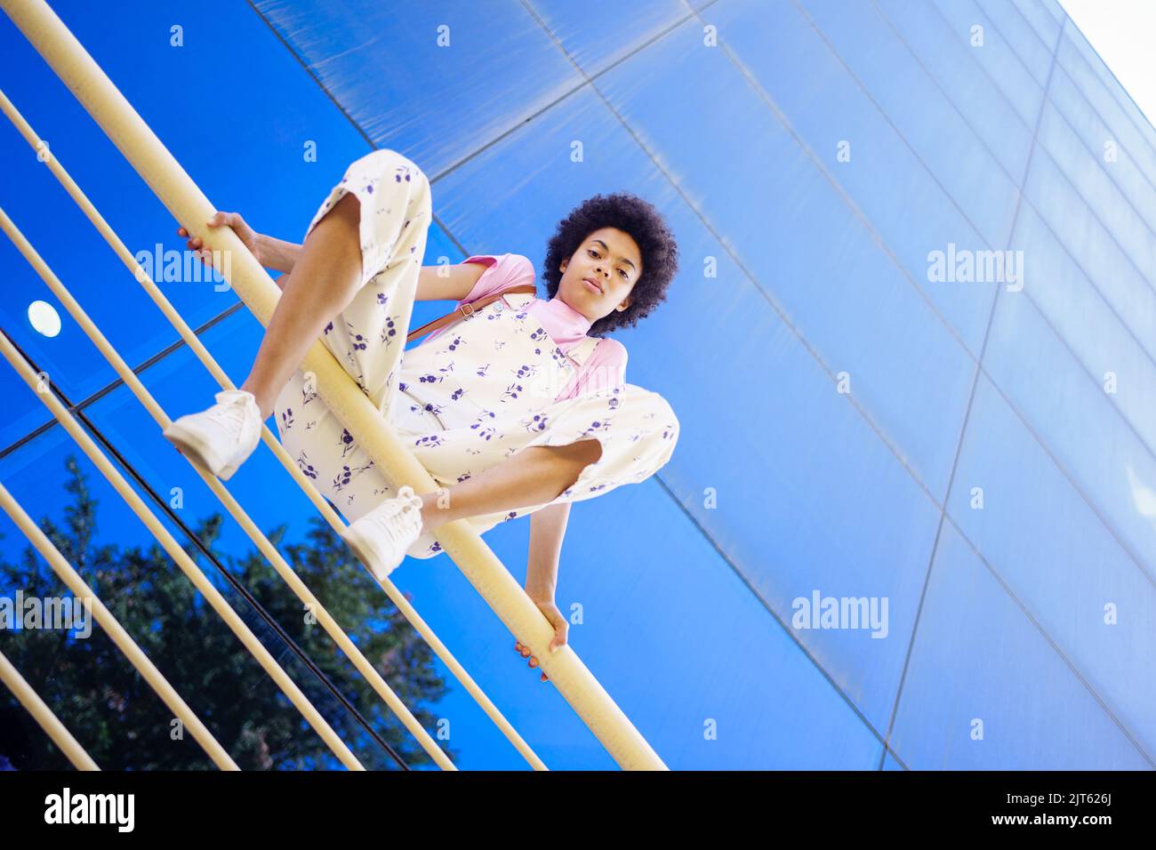 Serious black woman sitting on railing Stock Photo - Alamy
