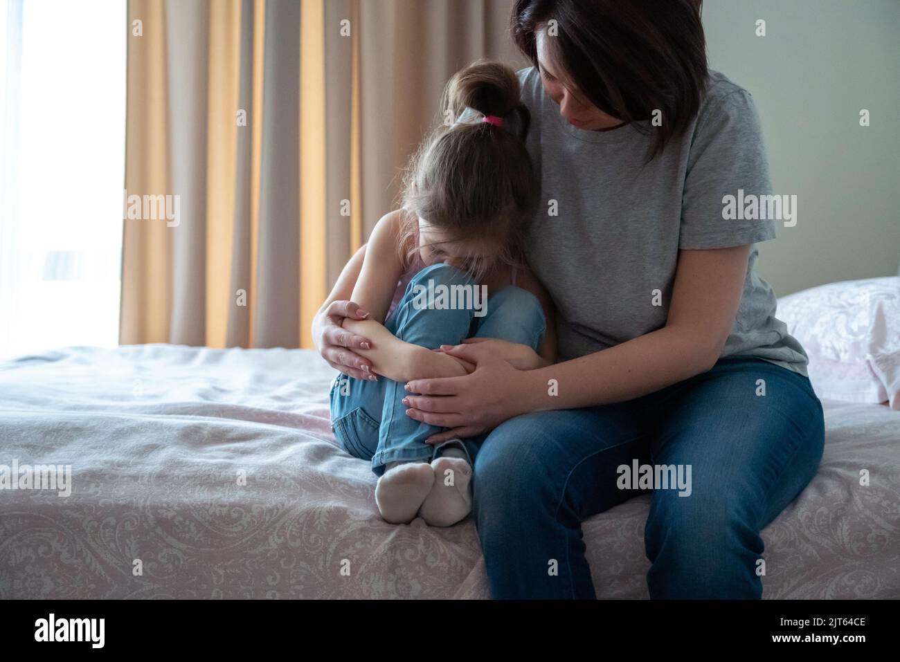Loving young mother touching upset little daughter, expressing support, young mum comforting ...