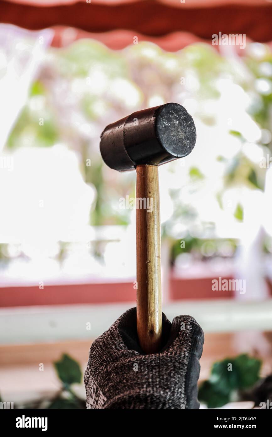 A vertical shot of a hand in a safety glove holding a rubber mallet in ...