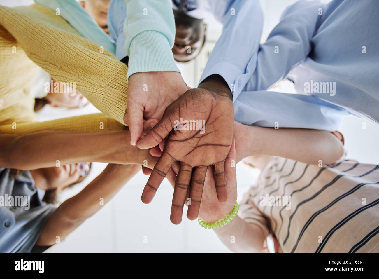 Low angle of diverse schoolchildren stacking hands and huddling in team ...