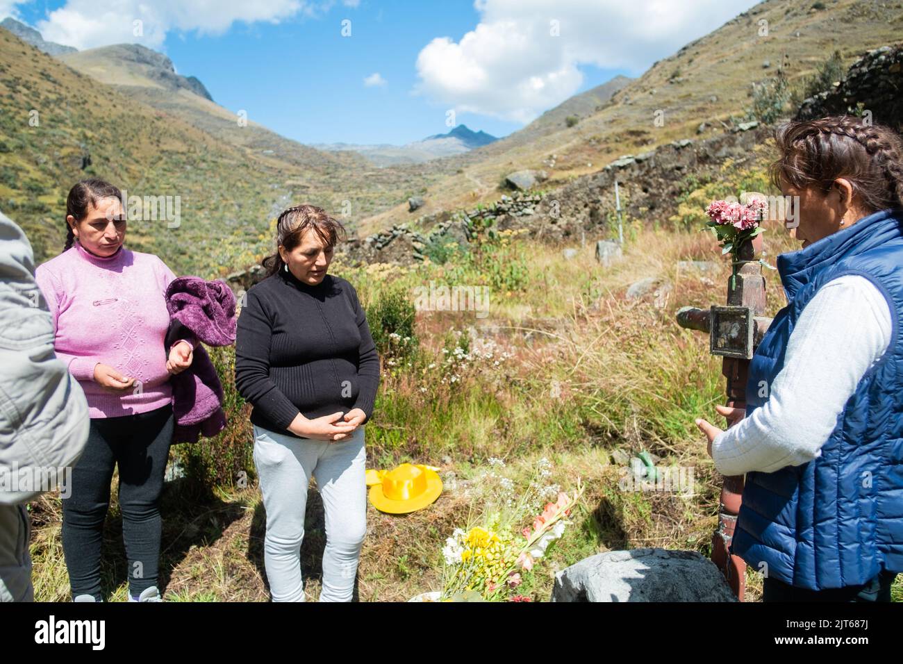 A group of people around the grave of a relative in a rural cemetery ...