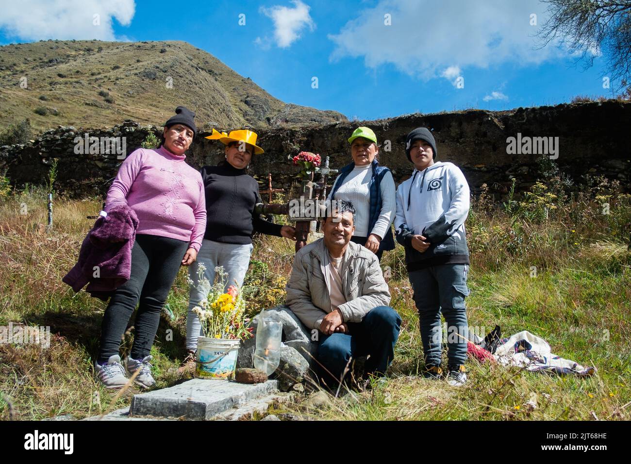 A group of people around the grave of a relative in a rural cemetery ...