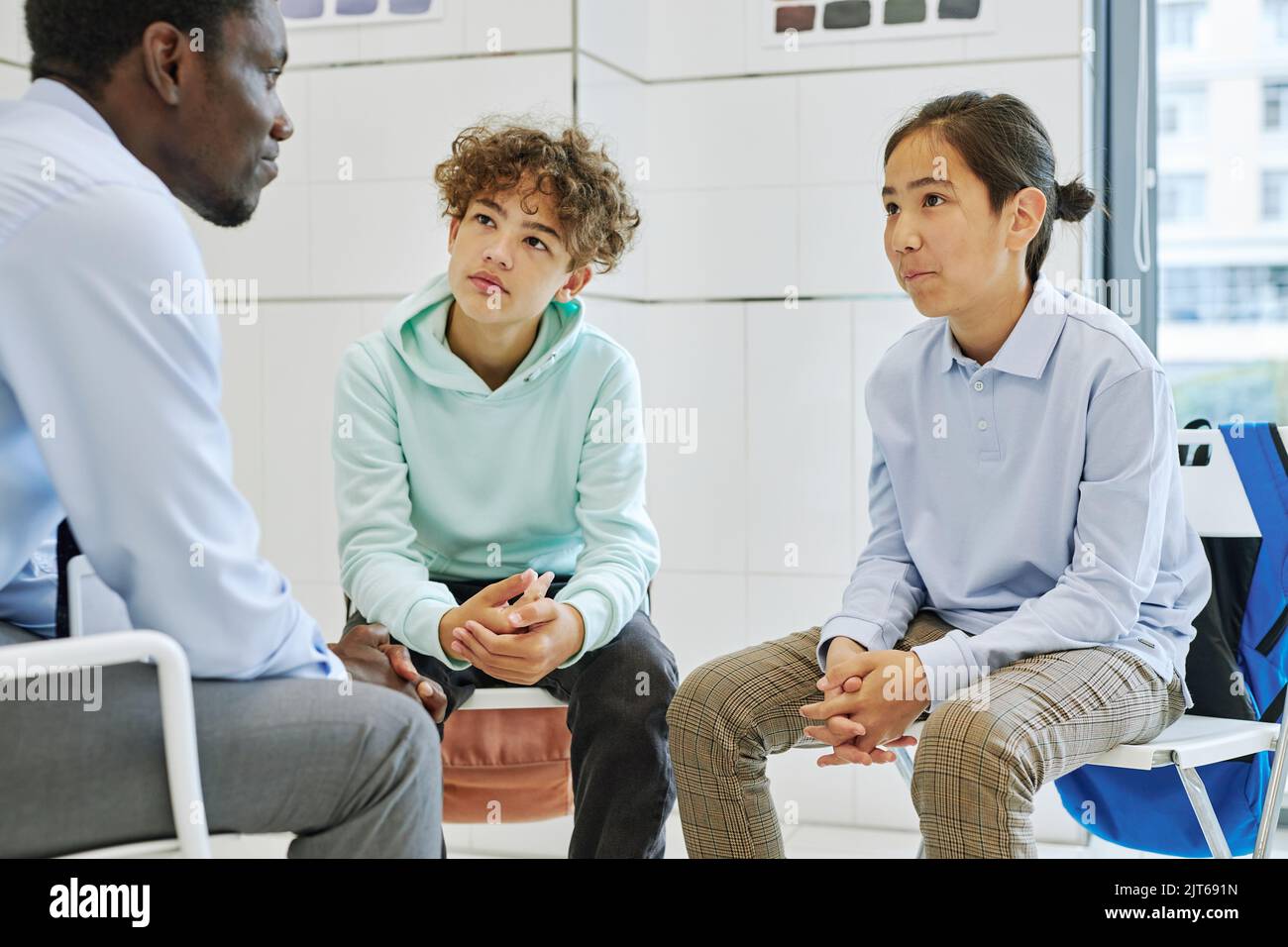 Portrait of two teen boys listening to counsellor in school therapy ...