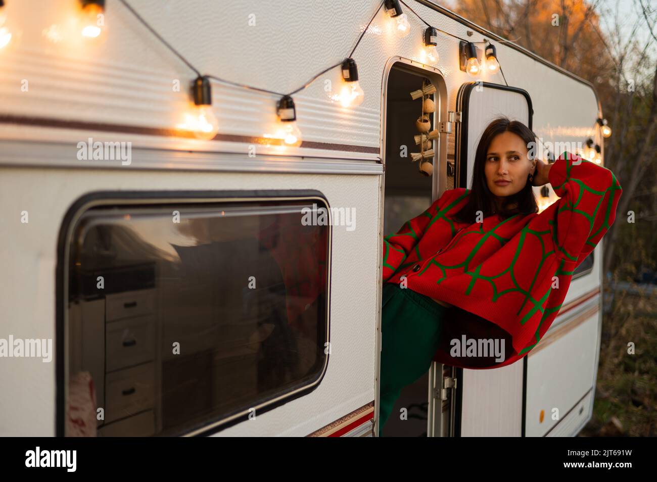 Caucasian woman in oversized red knitted jumper travels in motorhome in ...