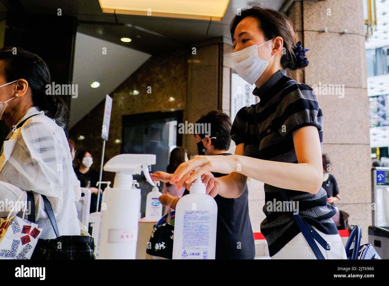 A woman disinfects her hands before entering a departmental store at ...