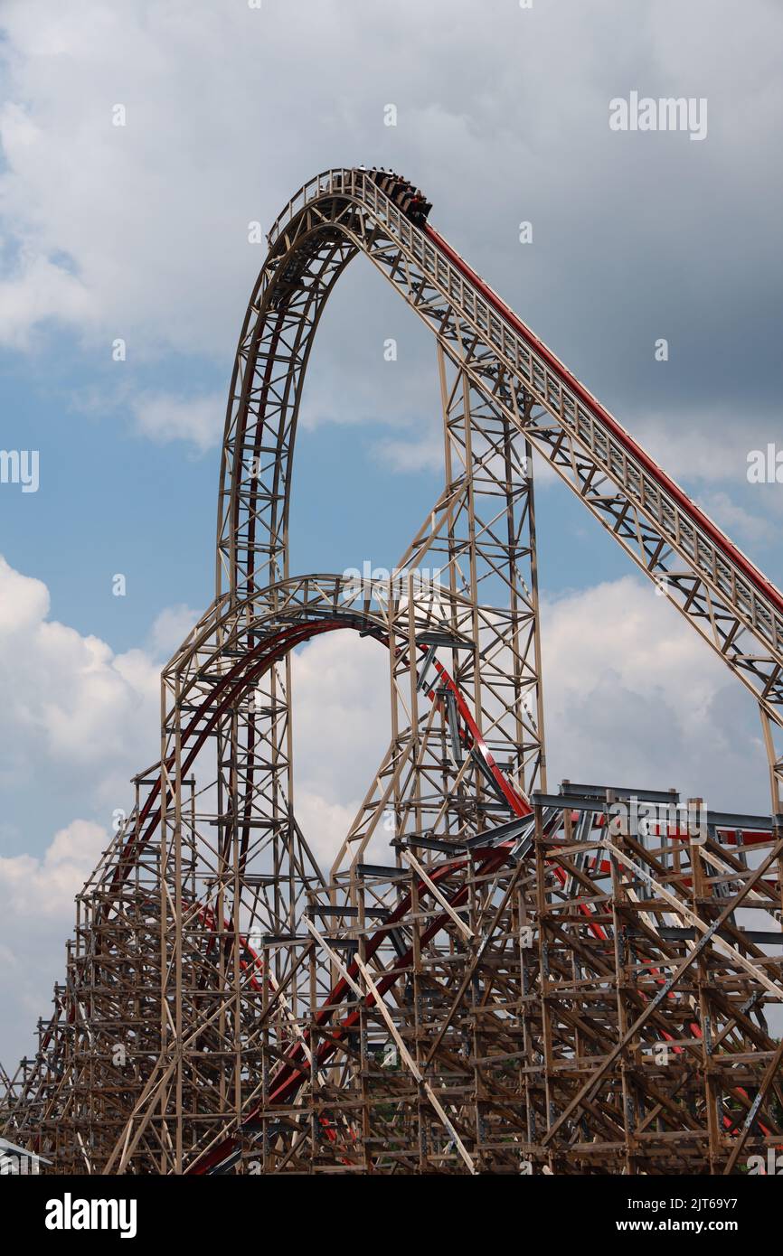 A vertical shot of a huge roller coaster in an amusement park in cloudy ...