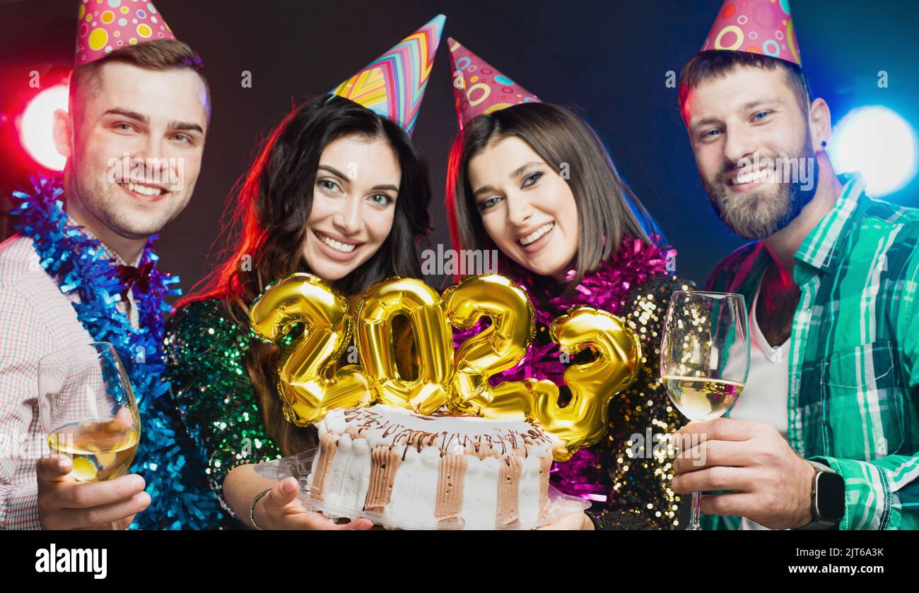 A group of friends hold a New Year's birthday cake with the numbers ...