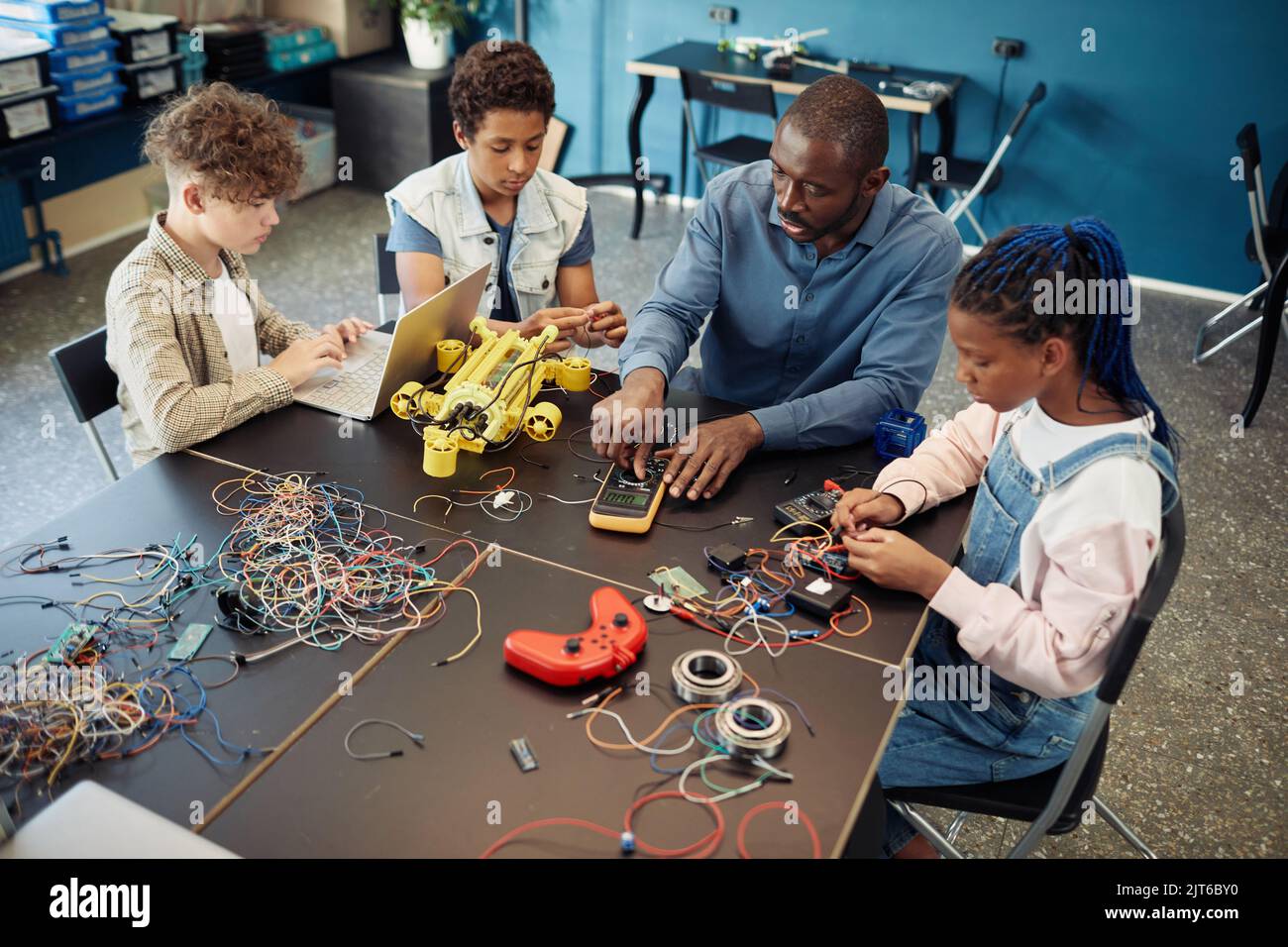 High angle view at diverse group of kids building robots during ...
