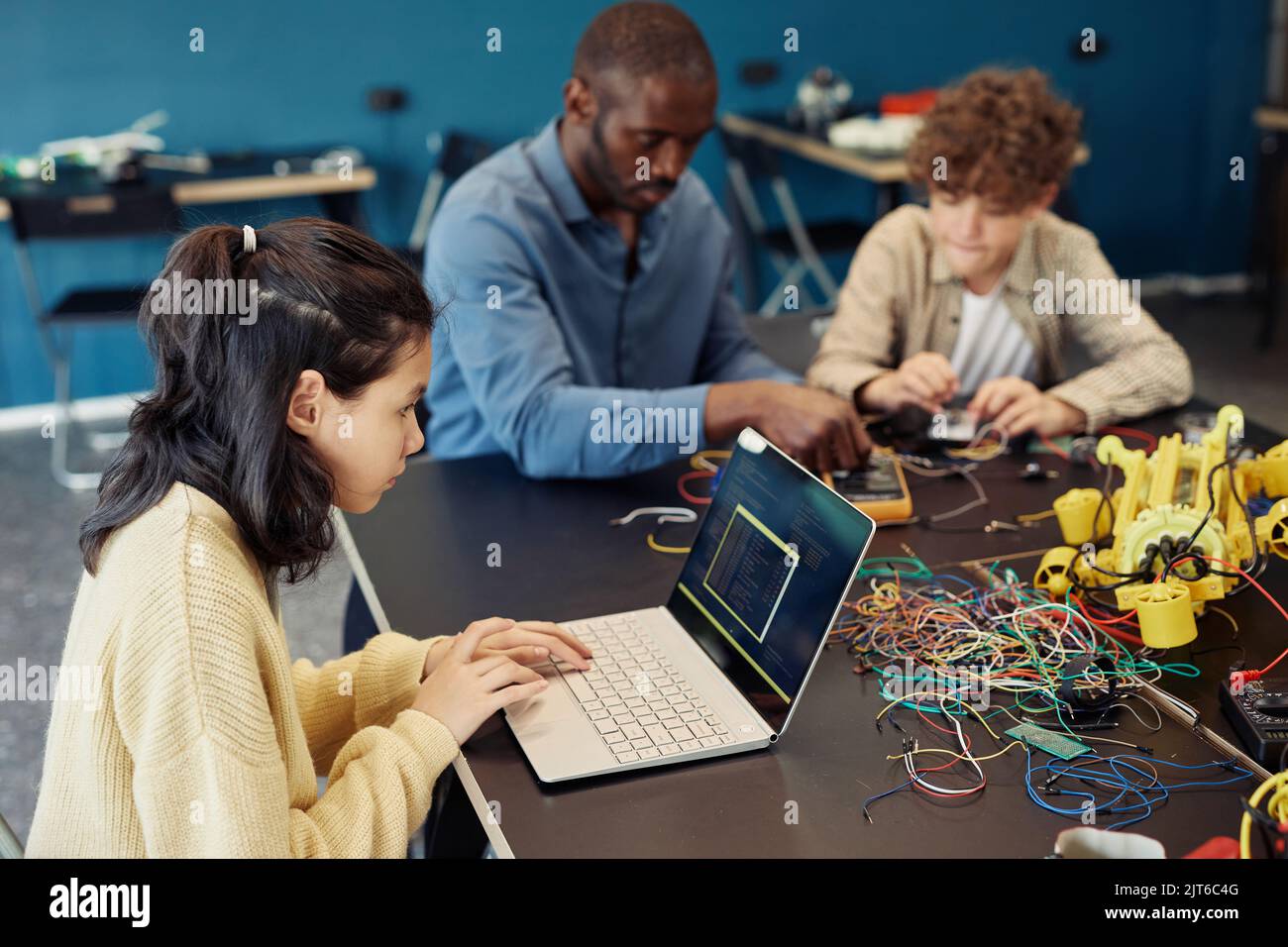 Side view portrait of young girl using laptop in engineering class and ...