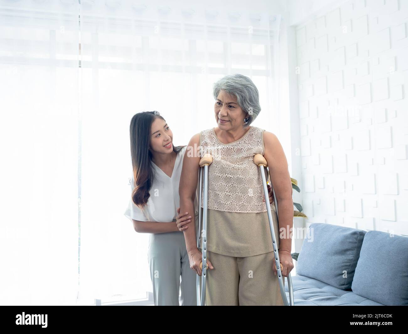 Elderly woman trying to walk on crutches standing held and supported in ...
