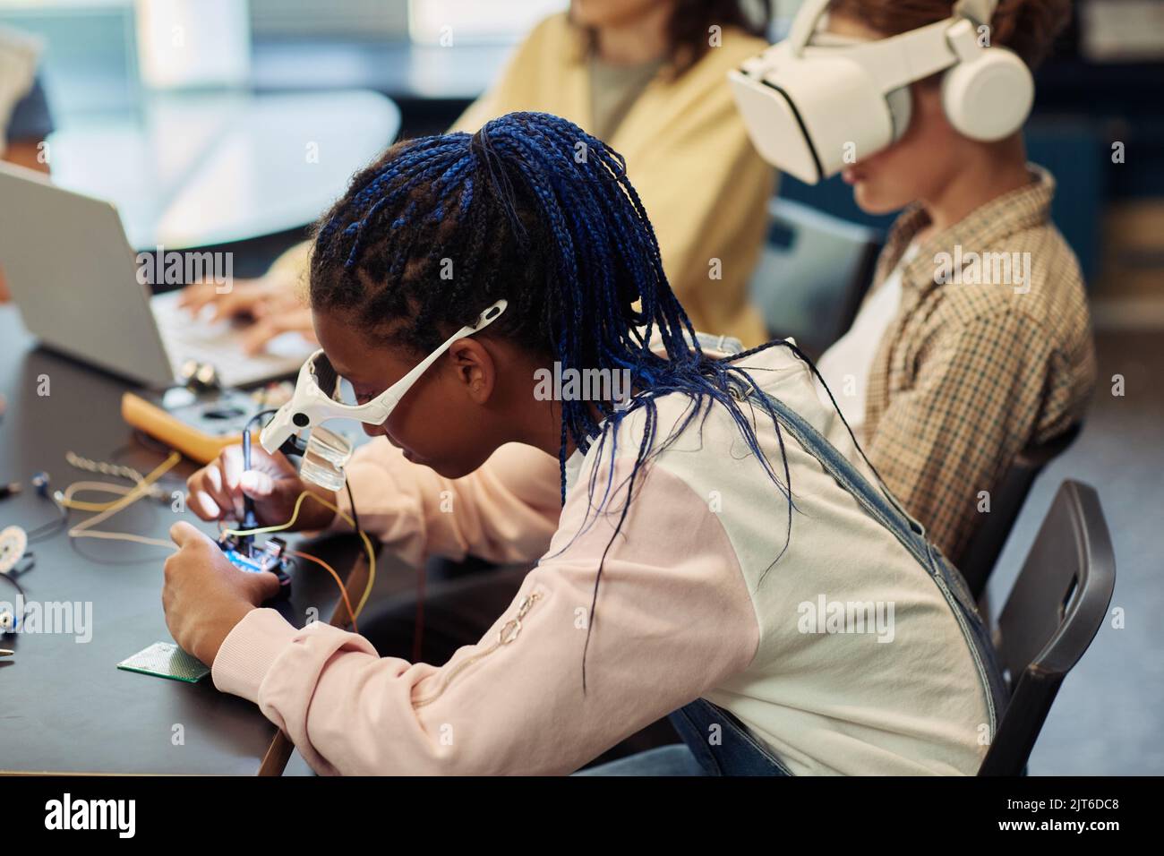 Side view portrait of black teenage girl connecting computer parts in ...