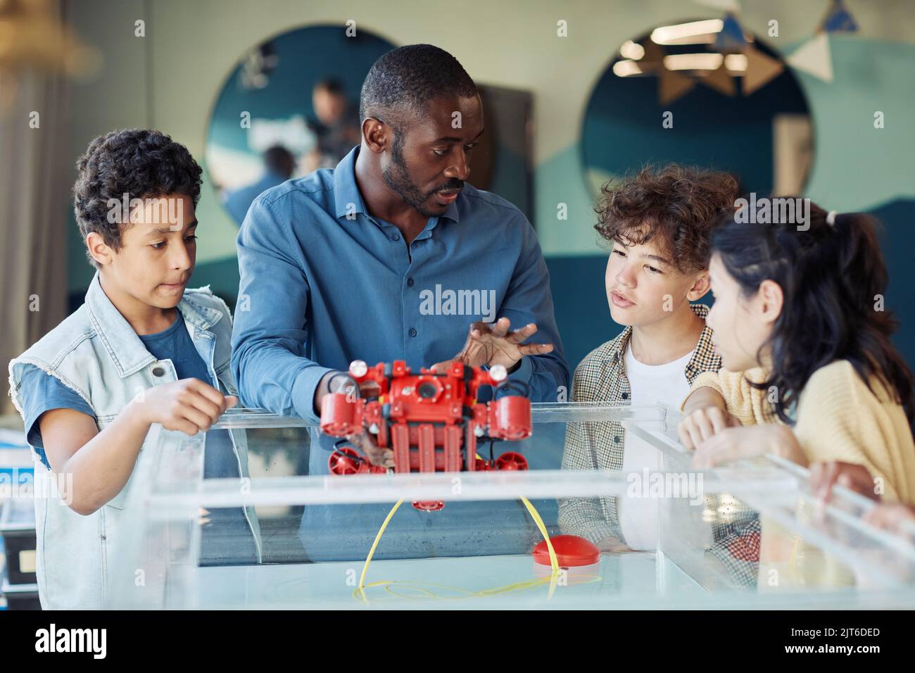 Portrait of black male teacher demonstrating robotic boat to diverse ...