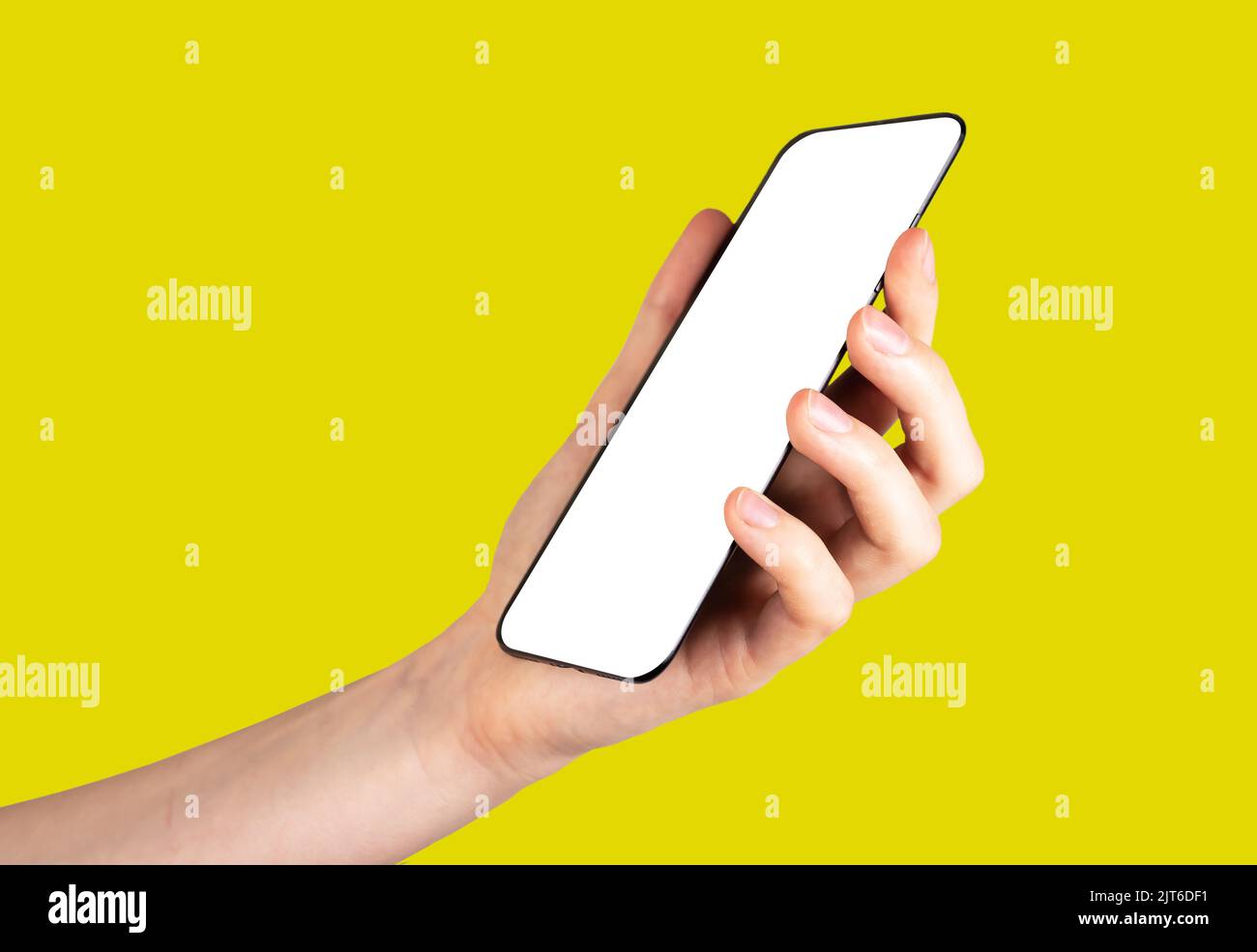 Hand holding phone mockup in angled position on yellow background ...