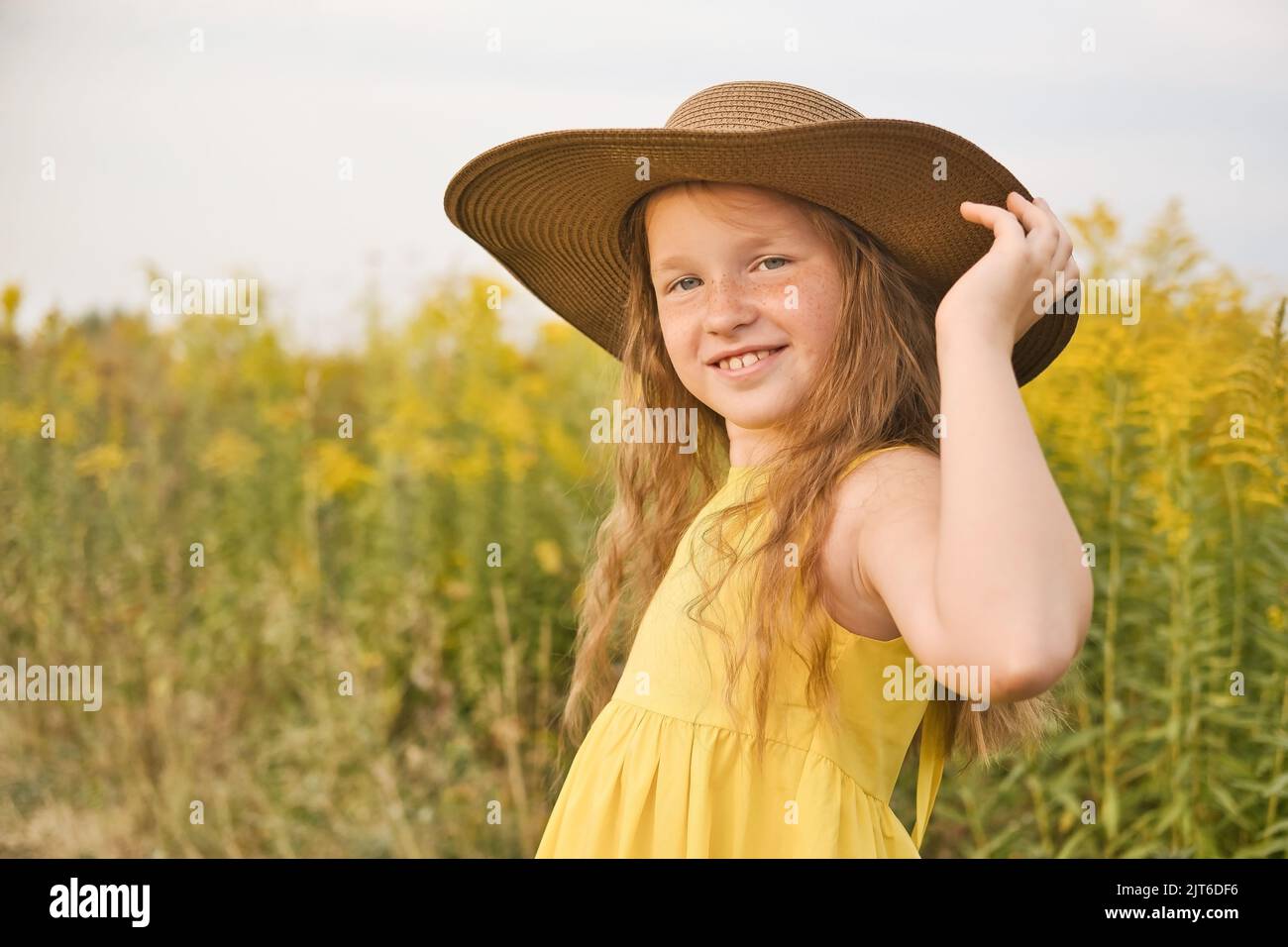 Happy and smiling cute little girl in yellow dress and hat walks in a ...