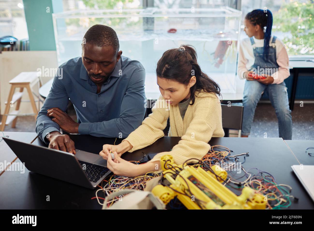 Portrait of young teenage girl building robots in engineering class ...