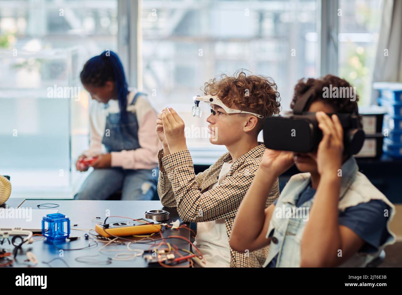 Side view portrait of two kids building robots in engineering class and ...