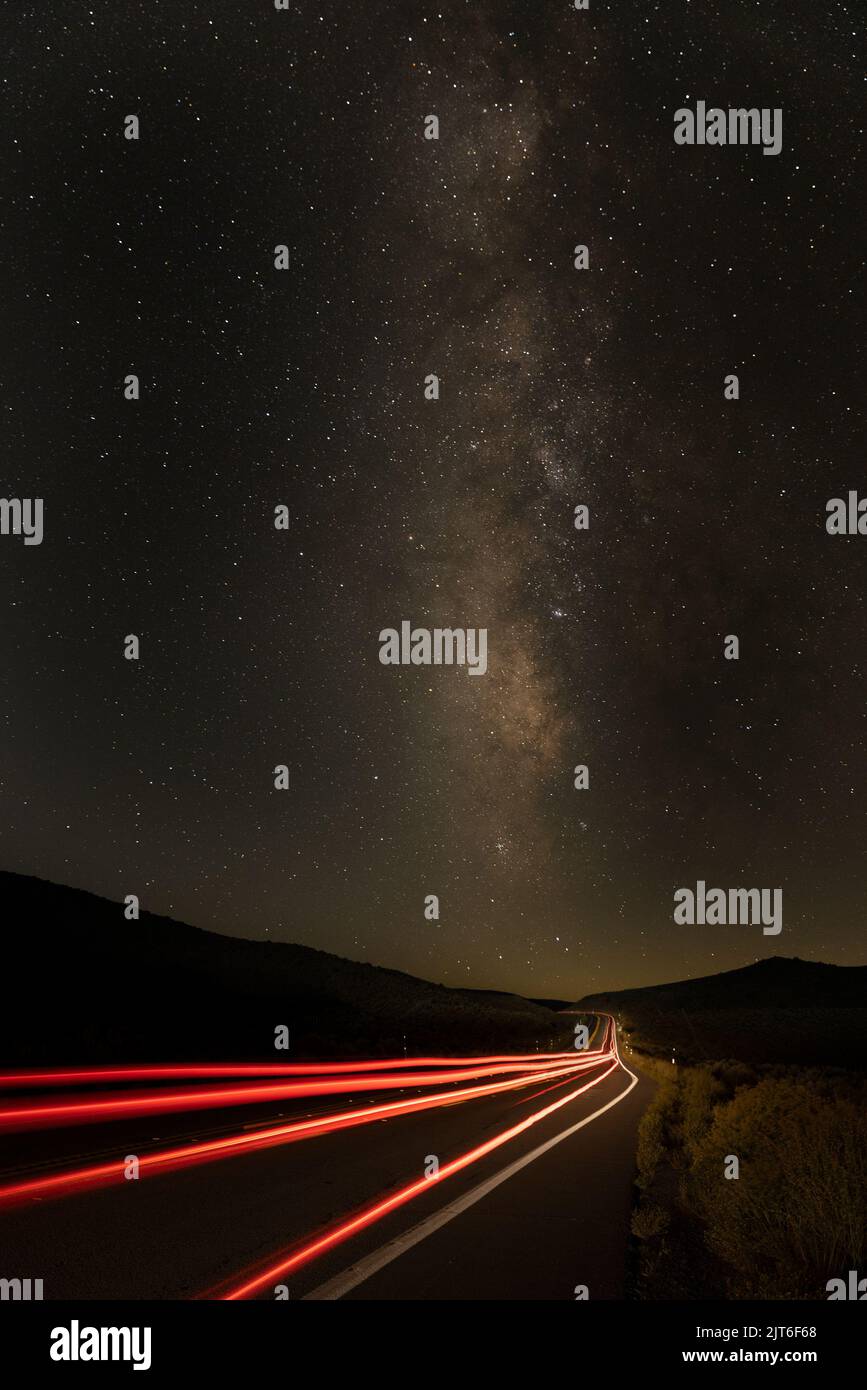 Long exposure traffic trails from tail lights stretching down the road ...