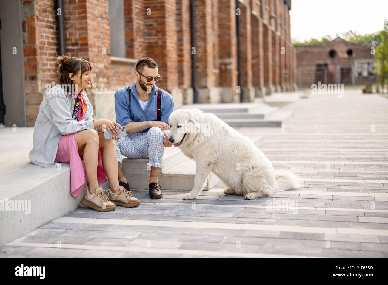 Stylish couple have fun and sit with their dog on a street Stock Photo ...