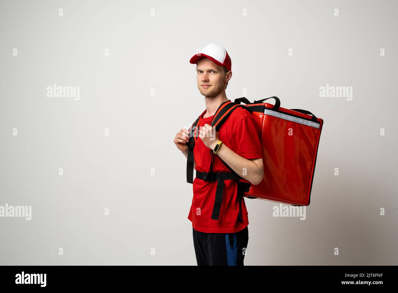 Delivery man in a red uniform and a cap carry red thermal backpack full ...