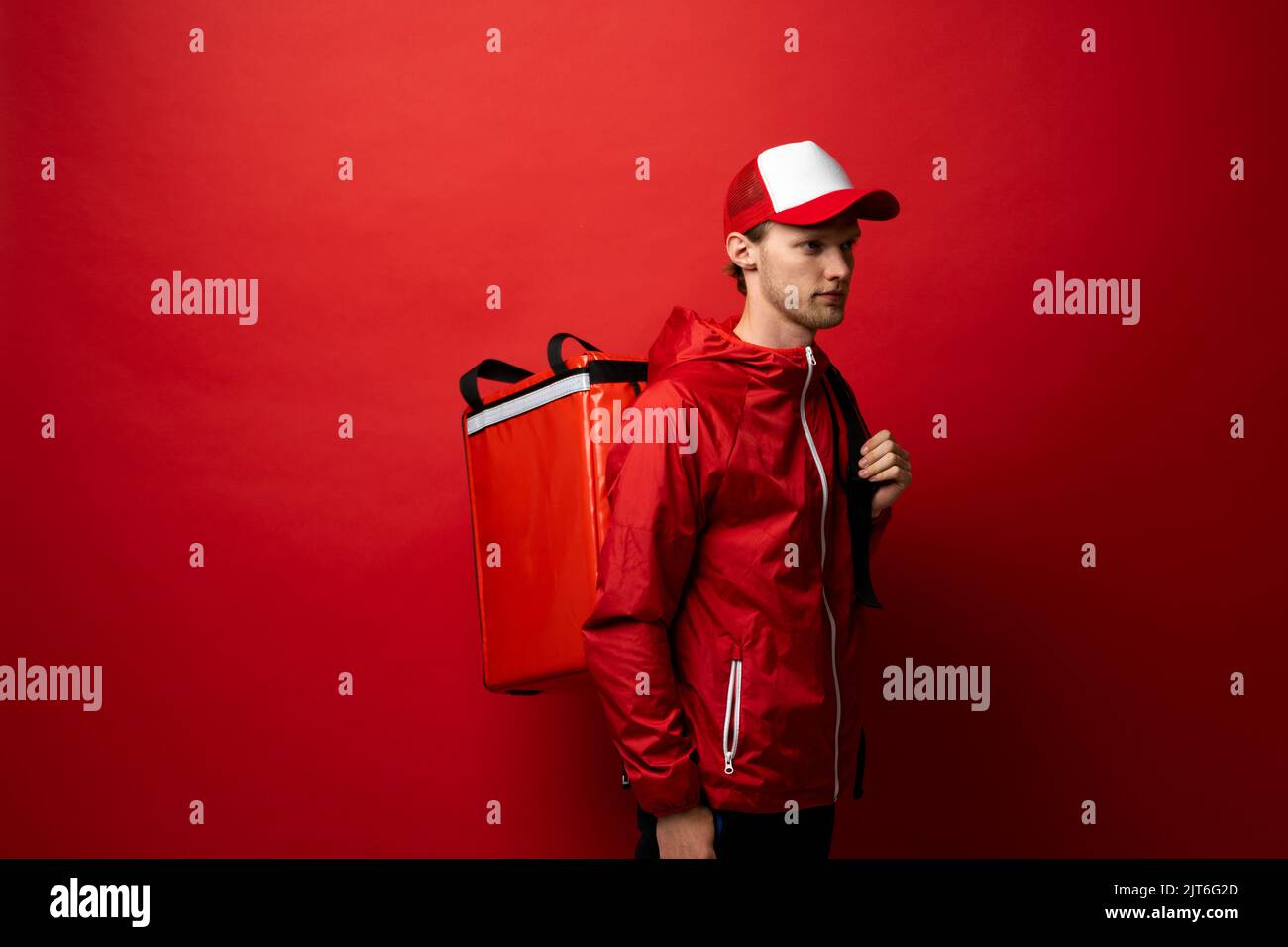 Delivery man in a red jacket and cap carry red thermal backpack full of ...