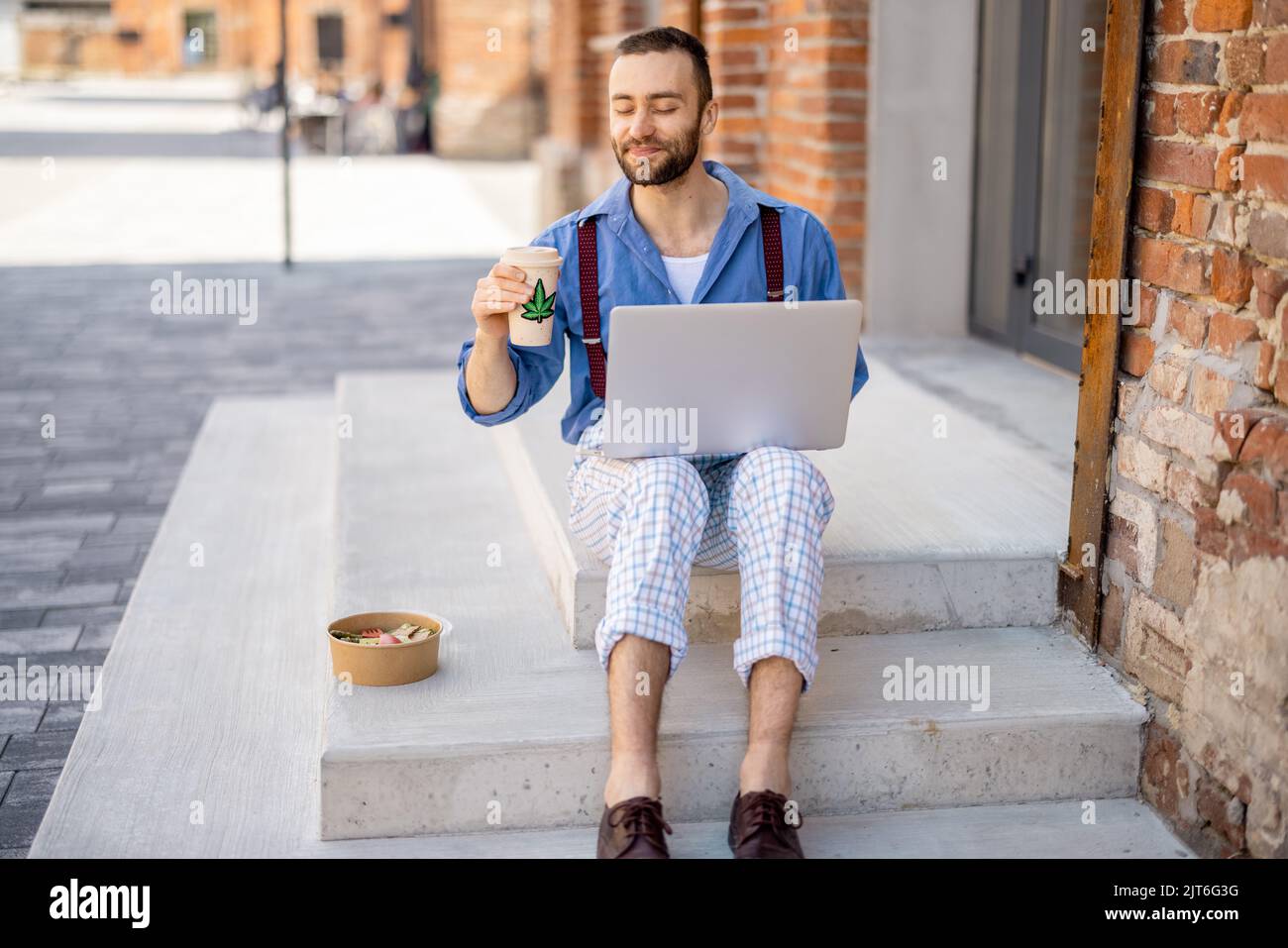 Stylish guy works on laptop computer on a street Stock Photo - Alamy