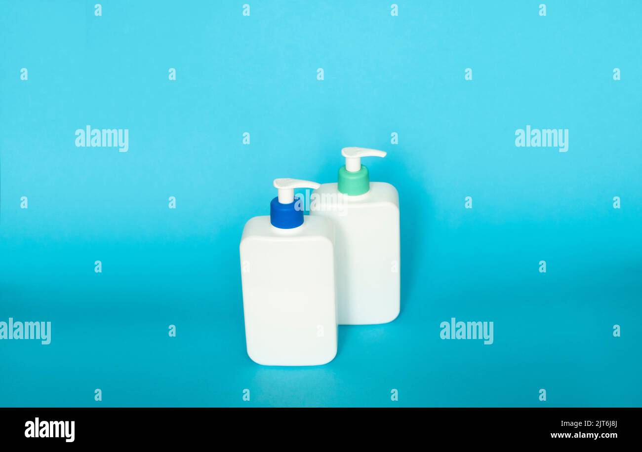 White cosmetic plastic bottles with black pump dispenser on blue ...