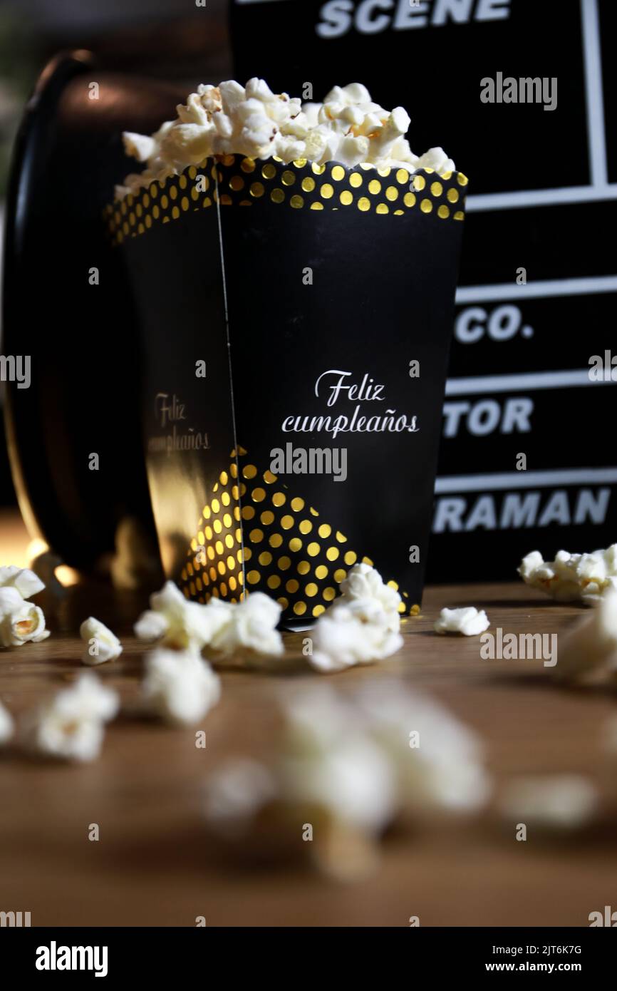 A vertical shot of popcorn in a black can in front of the movie clapper ...