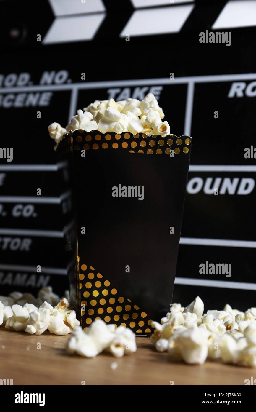 A vertical shot of popcorn in a black can in front of the movie clapper ...