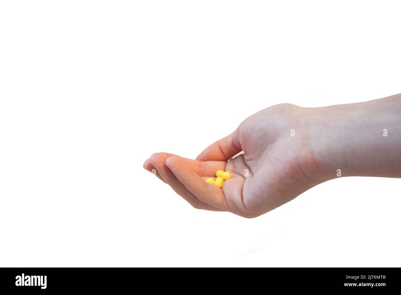 Isolated hand palm full of yellow circle pill capsules with the white ...