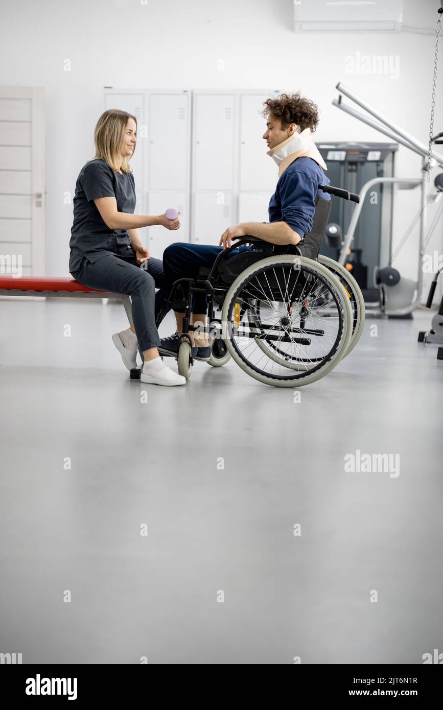 Rehabilitation specialist with guy on a wheelchair doing exercise Stock ...