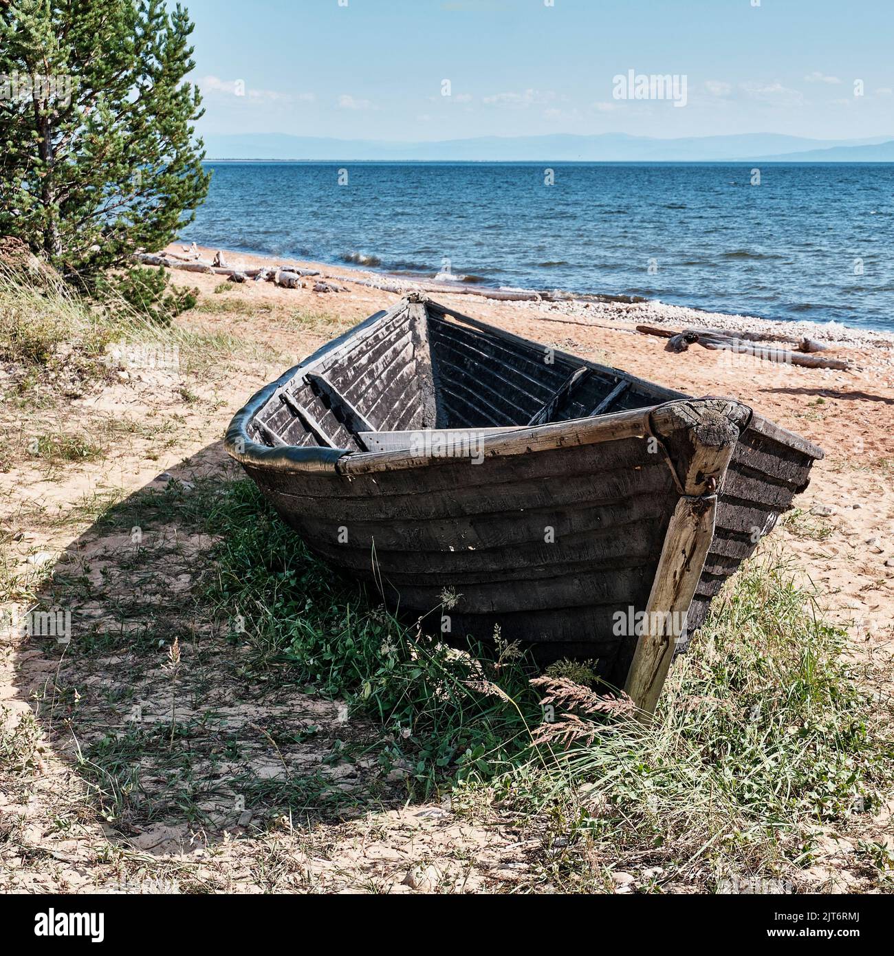 Old fishing wooden longboat on shore of Kultuk Bay. Lake Baikal ...