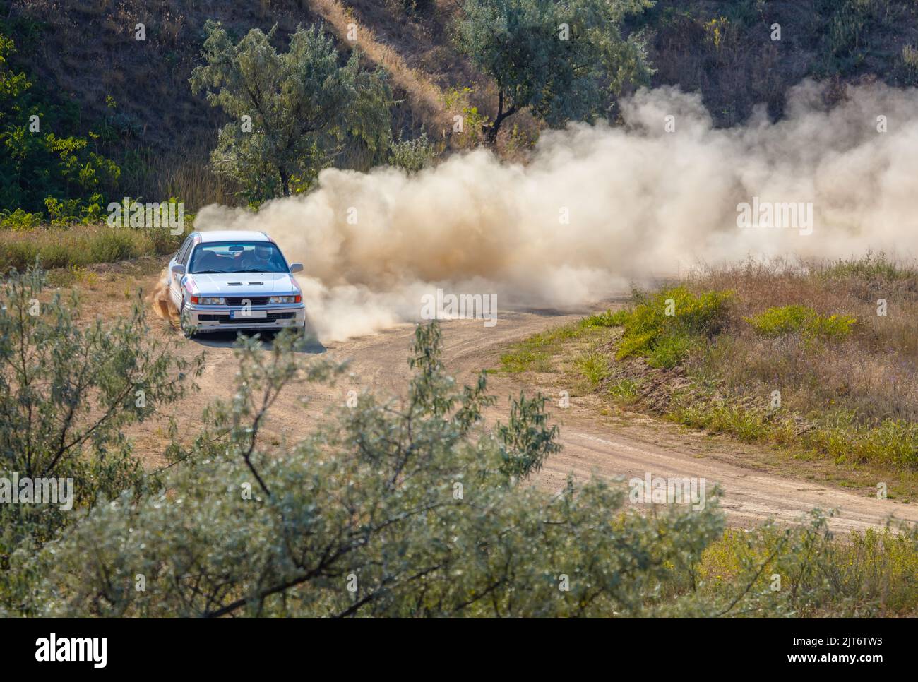 Sunny summer day. Dusty rally track. Sports car does a lot of dust in ...