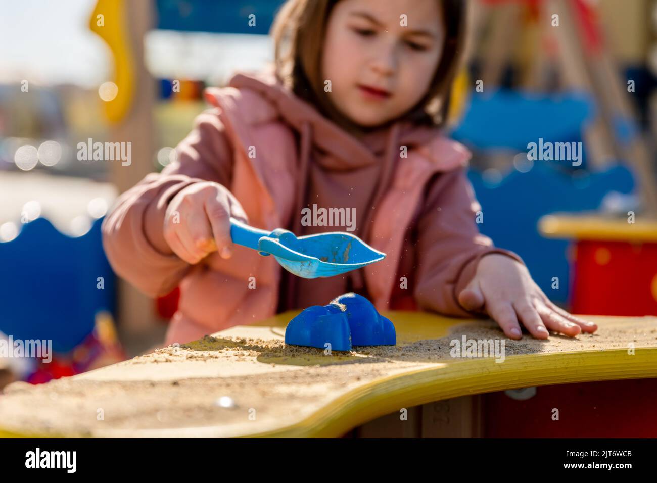 cute girl playing outside in the sandbox and making shapes out of a ...
