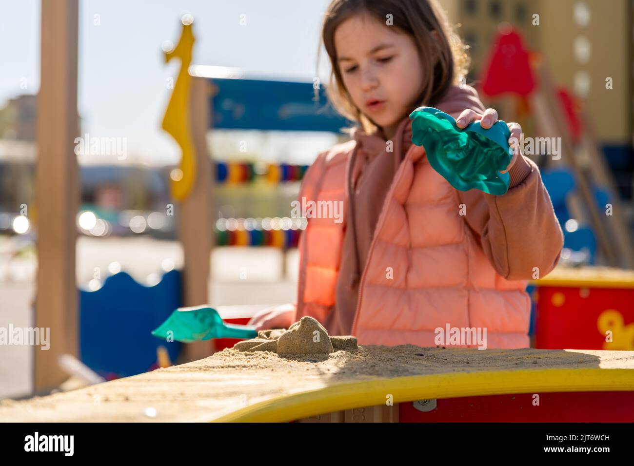 cute girl playing outside in the sandbox and making shapes out of a ...