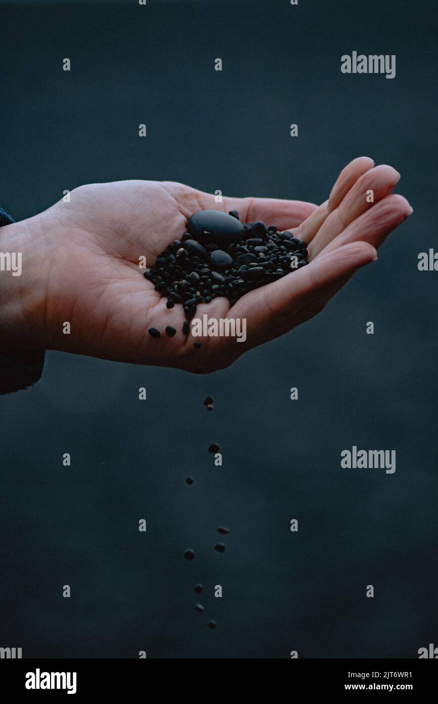 A vertical closeup shot of a hand holding a pile of small rocks with ...