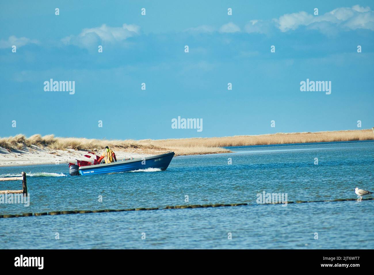 A beautiful calm sea view with a fisher on a small boat near sandy ...