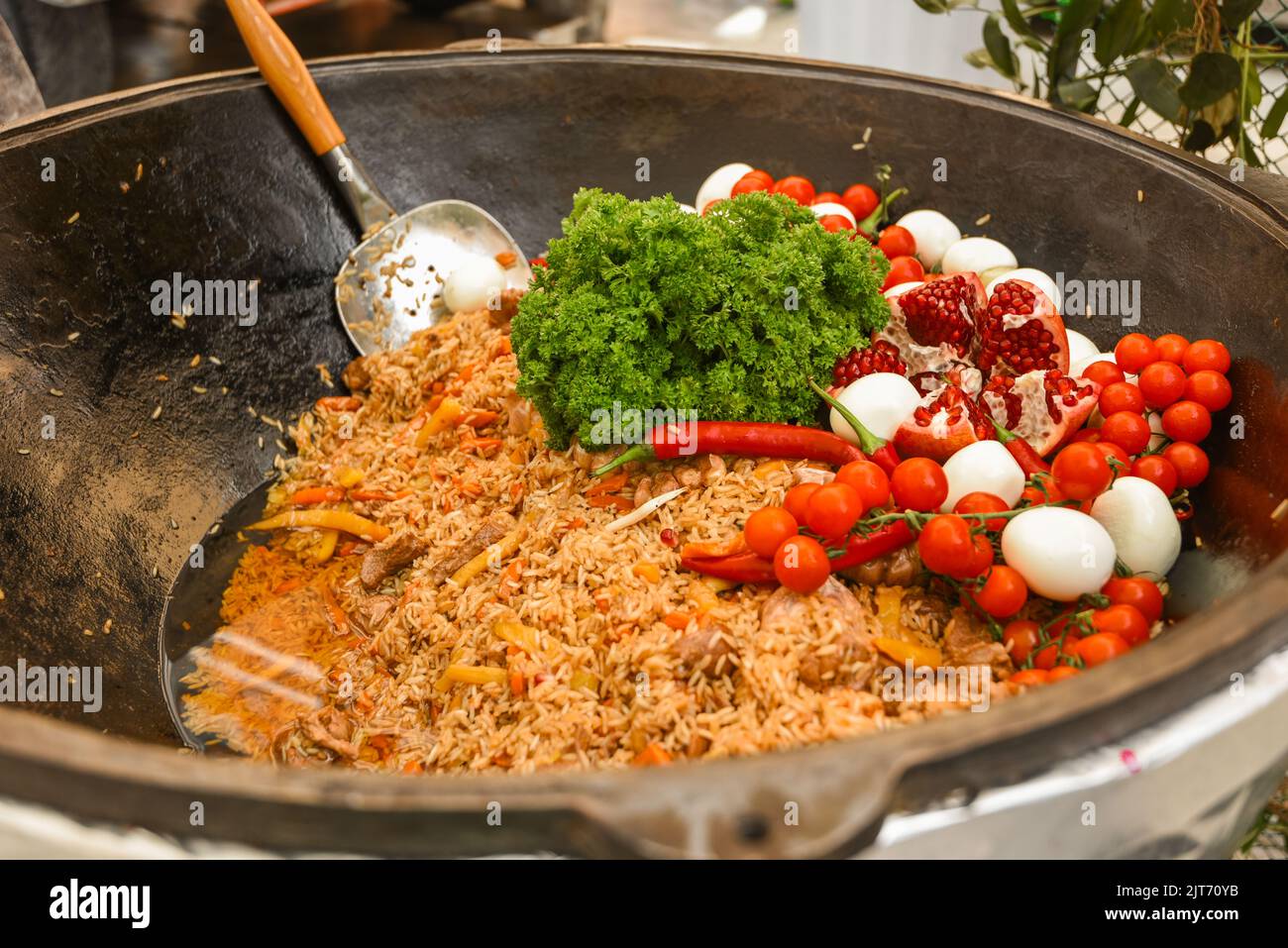 food festival. The cook prepares pilaf in a large cauldron. Stirring ...